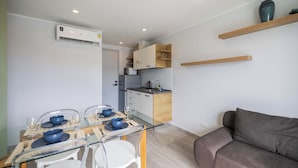 Espaço compacto com área de refeições, cozinha compacta e sofá.