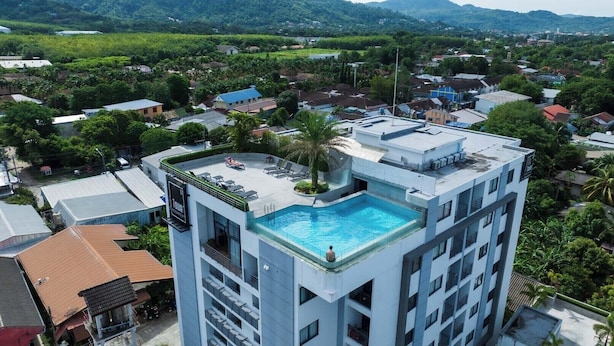 Um edifício alto com piscina no terraço e uma placa indicando ser um hotel.