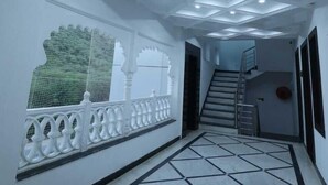 Um corredor com piso de azulejos, escada e corrimão decorativo.