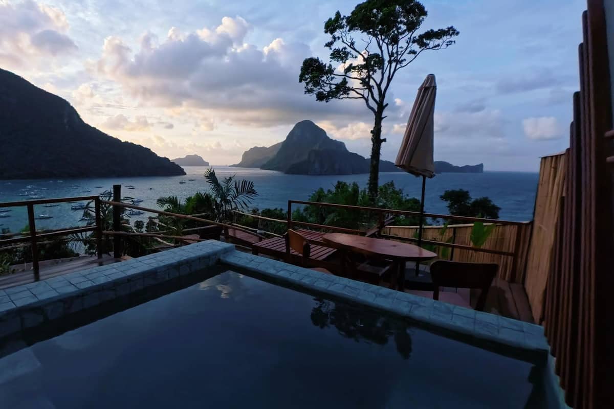 Uma área de piscina com vista para o mar e montanhas.