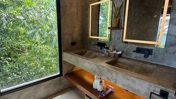 Casa de banho moderna com duas pias, um espelho grande e uma janela com vista para o verde.