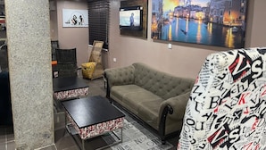 Uma sala de estar com um sofá, duas mesas, uma televisão e obras de arte nas paredes.