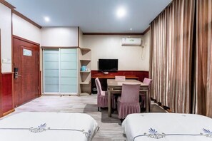 Quarto de hotel com duas camas, uma escrivaninha com cadeira, televisão e guarda-roupa.