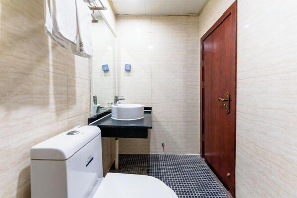 Uma casa de banho com sanita, lavatório e zona de duche.