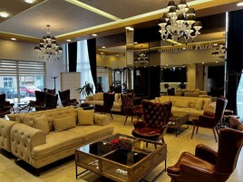 Um hall amplo com uma grande área de estar, incluindo sofás e poltronas, uma mesa de centro com flores e um lustre.
