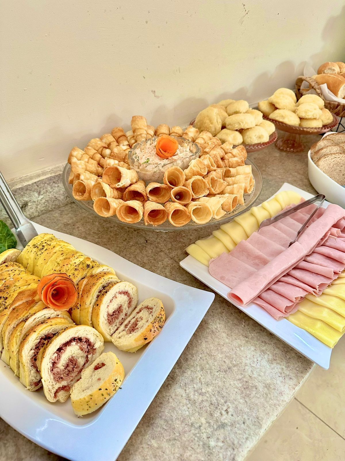 Buffet com diversos alimentos, incluindo doces, queijos e carnes.