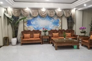 Sala de estar em estilo tradicional, com móveis de madeira, uma grande tapeçaria decorativa e plantas em vasos.