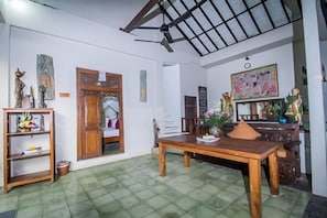 Quarto com uma mesa de jantar de madeira, estante e espelho decorativo.