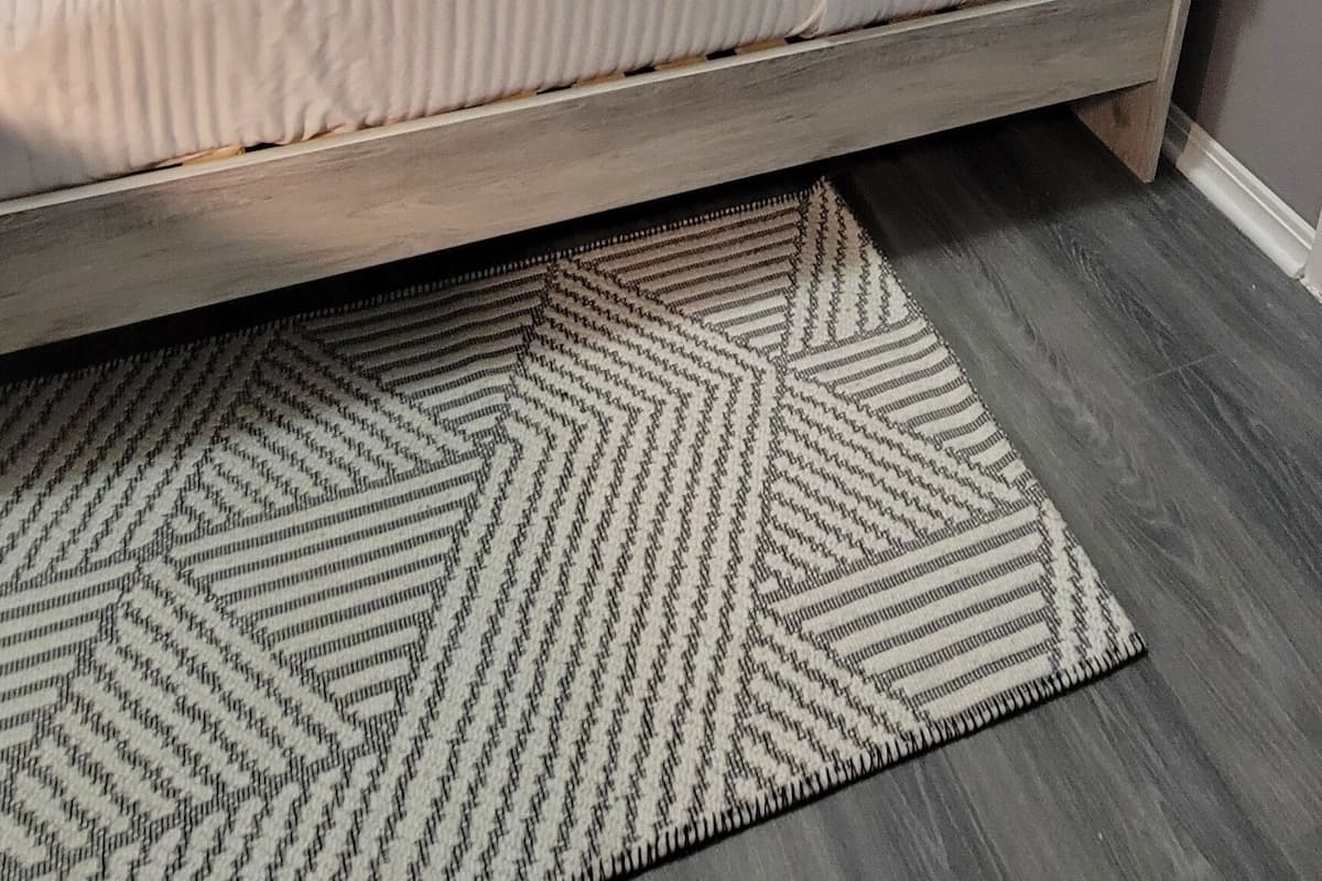 Uma cama com cabeceira, mesa de cabeceira e um tapete estampado.