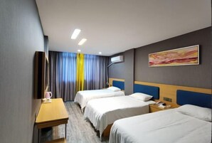 Quarto de hotel com duas camas, uma escrivaninha, uma cadeira, uma televisão e um quadro na parede.