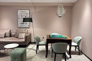 Uma sala de estar moderna com sofá, mesa de centro, mesa de jantar com cadeiras, abajur e lustre.
