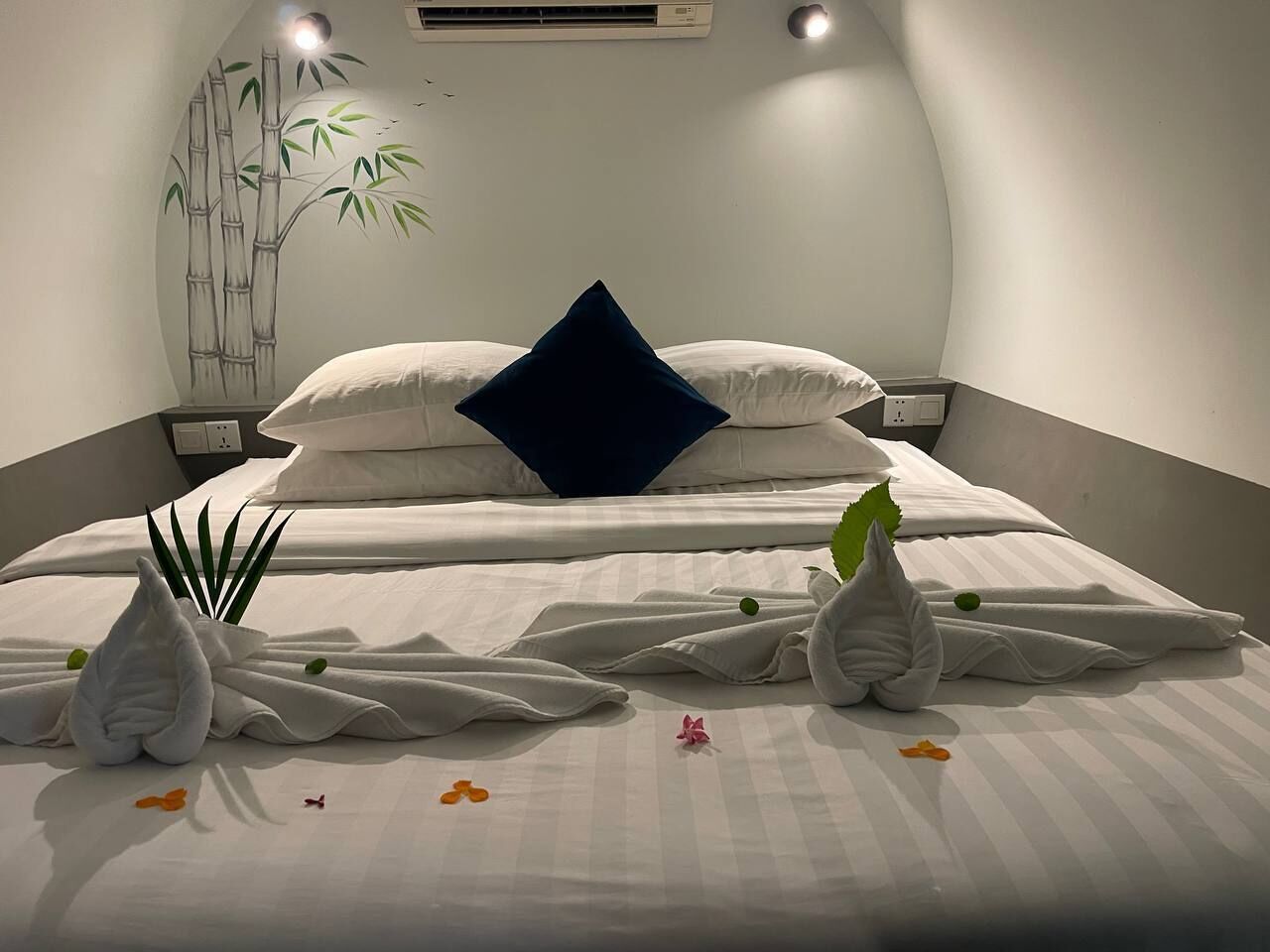 Quarto de hotel com cama, almofadas e um mural na parede.