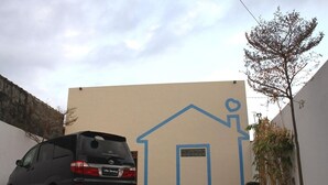 Uma carrinha preta estacionada em frente a um edifício com um grande símbolo de casa azul na parede.