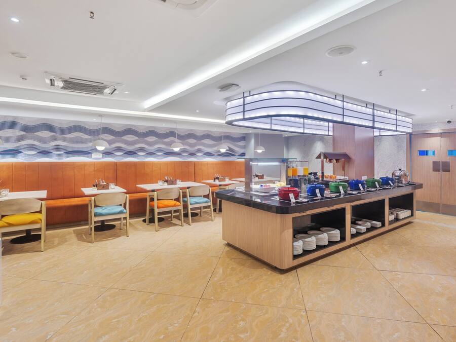 Restaurante moderno com balcão central, área de estar e parede decorativa.
