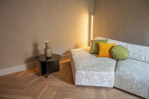 Uma sala de estar moderna com um sofá, uma mesinha lateral e um vaso.