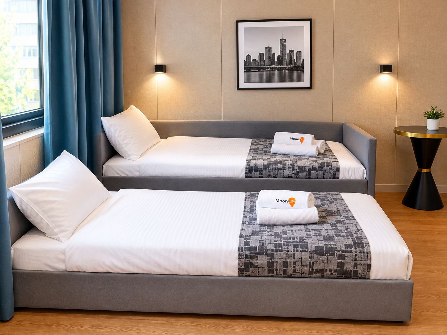 Quarto de hotel com duas camas, um quadro com vista para a cidade e uma mesa pequena com uma planta.