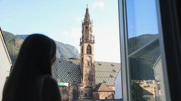 Vista de uma igreja com uma torre alta e telhado trabalhado, vista pela janela.