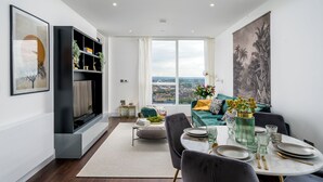 Uma sala de estar moderna com área de jantar, janelas amplas e vista para a cidade.