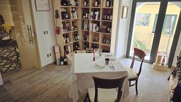 Uma área de refeições com uma mesa posta para dois, rodeada por estantes de madeira cheias de garrafas de vinho.