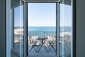 Varanda com mesa e cadeiras com vista para a praia.