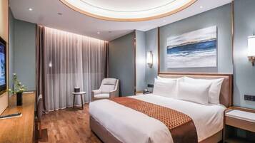 Quarto de hotel moderno com uma cama grande, TV, escrivaninha e vista para o oceano.
