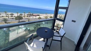 Varanda com mesa e cadeiras, com vista para a praia e o oceano.
