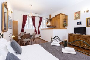 Quarto de hotel com cama, área de refeições, televisão e armários de madeira.