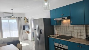 Uma cozinha moderna com armários verde-água, uma geladeira de aço inoxidável e um forno embutido.