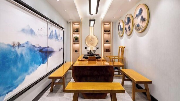 Uma área de refeições com mesa e bancos de madeira, um quadro grande na parede e prateleiras com objetos decorativos.