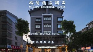 Um hotel com fachada moderna, exibindo uma placa de destaque com a inscrição "O'STIN Boutique Hotel".