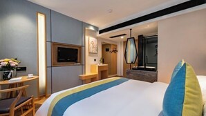 Quarto de hotel moderno com uma cama grande, uma escrivaninha e uma televisão.