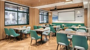 Uma sala de jantar moderna com lambris de madeira, amplas janelas e cadeiras estofadas em verde.