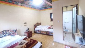 Quarto com cama, mesa de cabeceira, espelho e televisão.