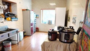 Uma cozinha com fogão, geladeira, janela e diversos eletrodomésticos na bancada.