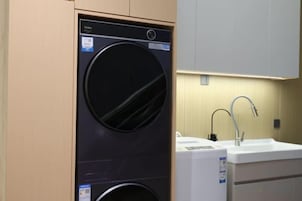 Uma área de lavanderia compacta, com máquina de lavar e secadora frontais, pia e armário superior.