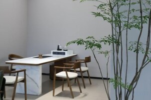 Uma sala de conferências com uma mesa comprida, várias cadeiras e um vaso de planta.