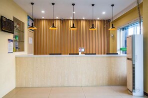 Área de recepção com painel de parede de madeira, balcão, luminárias pendentes e um grande aparelho de ar condicionado.