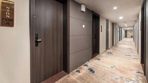 Corredor de hotel com portas de madeira, piso coberto por carpete e placa indicando a sala 8708.