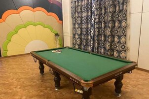 Uma mesa de bilhar com pano verde, uma bola branca e uma garrafa de água.
