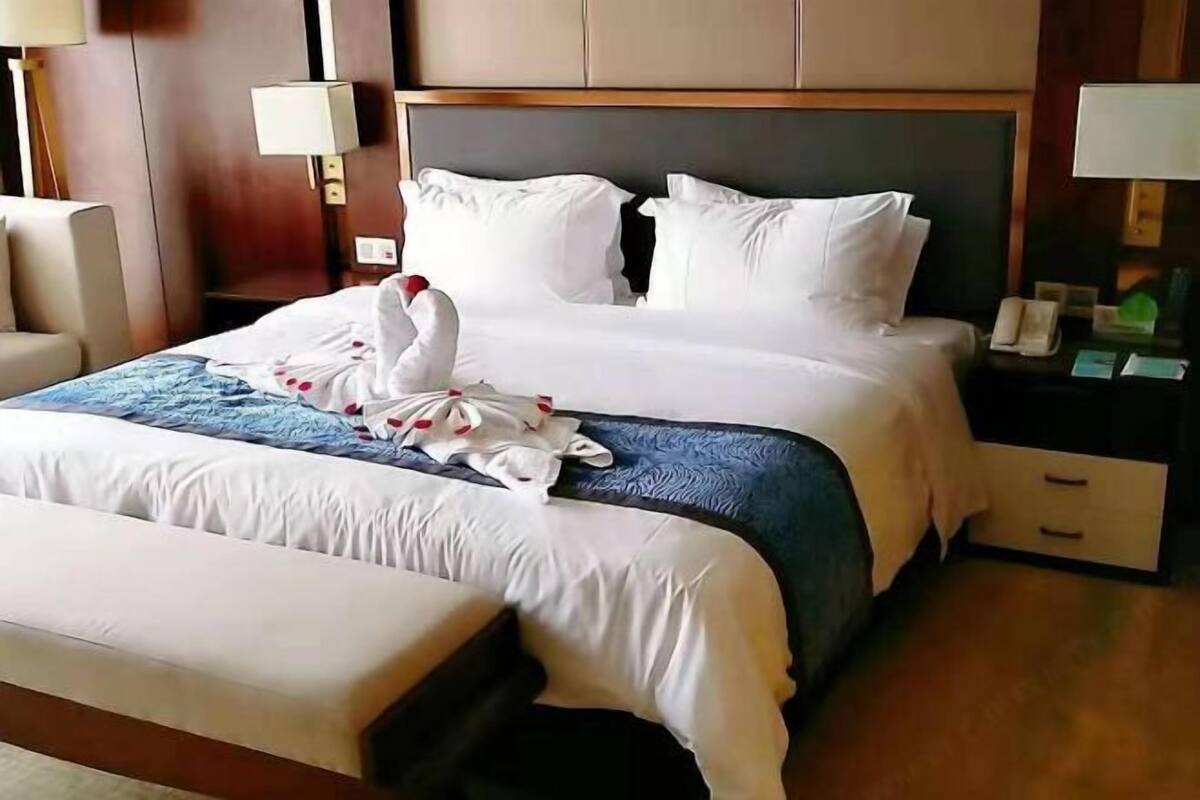 Quarto de hotel com uma cama grande, uma mesa de cabeceira, uma luminária e uma cadeira.