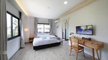 Quarto de hotel moderno com uma cama grande, uma escrivaninha com cadeira, televisão e uma janela com cortinas.