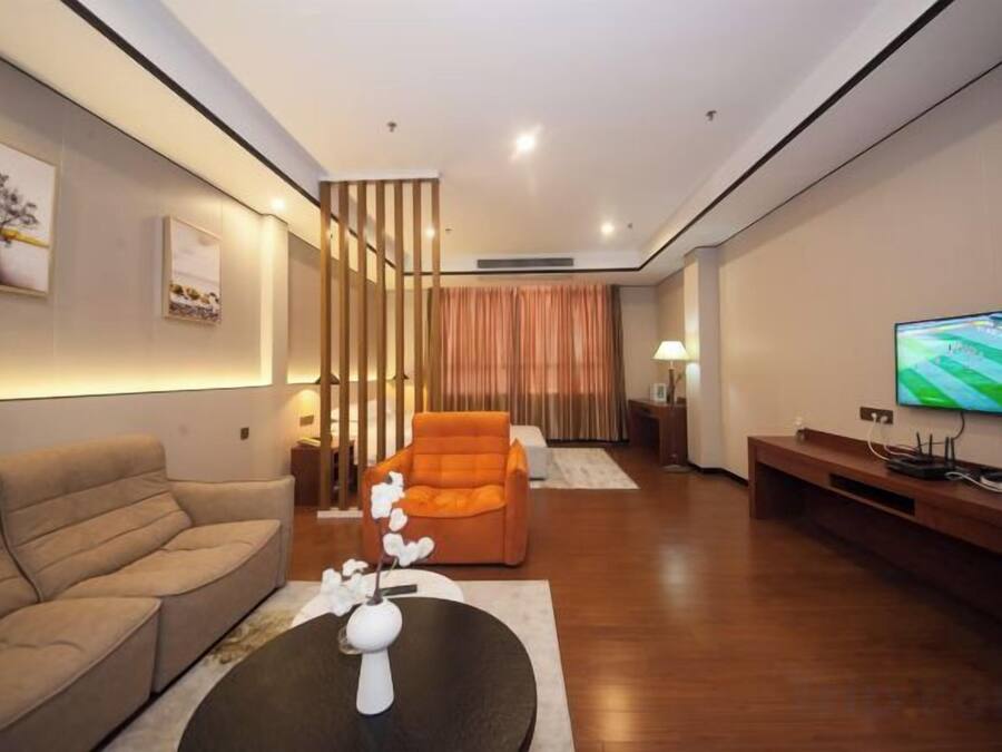 Uma sala de estar moderna com sofá, mesa de centro, televisão e uma planta decorativa.