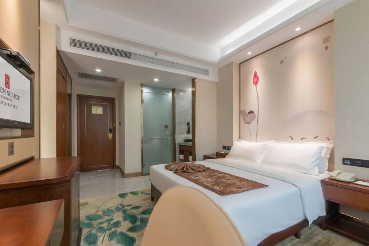 Quarto de hotel com cama, mesa de cabeceira e escrivaninha com cadeira.