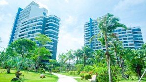 Um hotel moderno com vários edifícios altos, rodeado por vegetação exuberante e palmeiras.