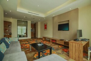 Sala de estar moderna com sofá, mesa de centro, televisão e mobiliário de madeira.