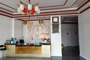 Uma área de recepção com balcão, relógio e um painel de cardápio fixado na parede.