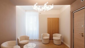 Uma sala de estar moderna com piso de madeira, luminária de teto branca e porta de madeira.