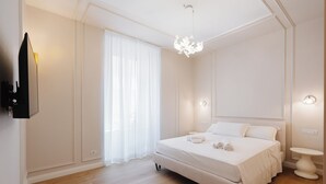 Um quarto moderno com uma cama grande, um candelabro e uma televisão na parede.
