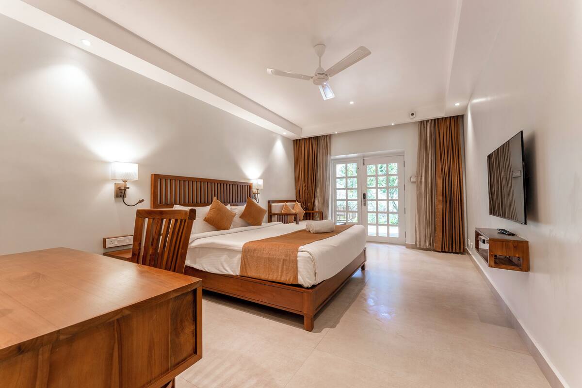 Quarto de hotel moderno com cama de madeira, escrivaninha e televisão de tela plana.