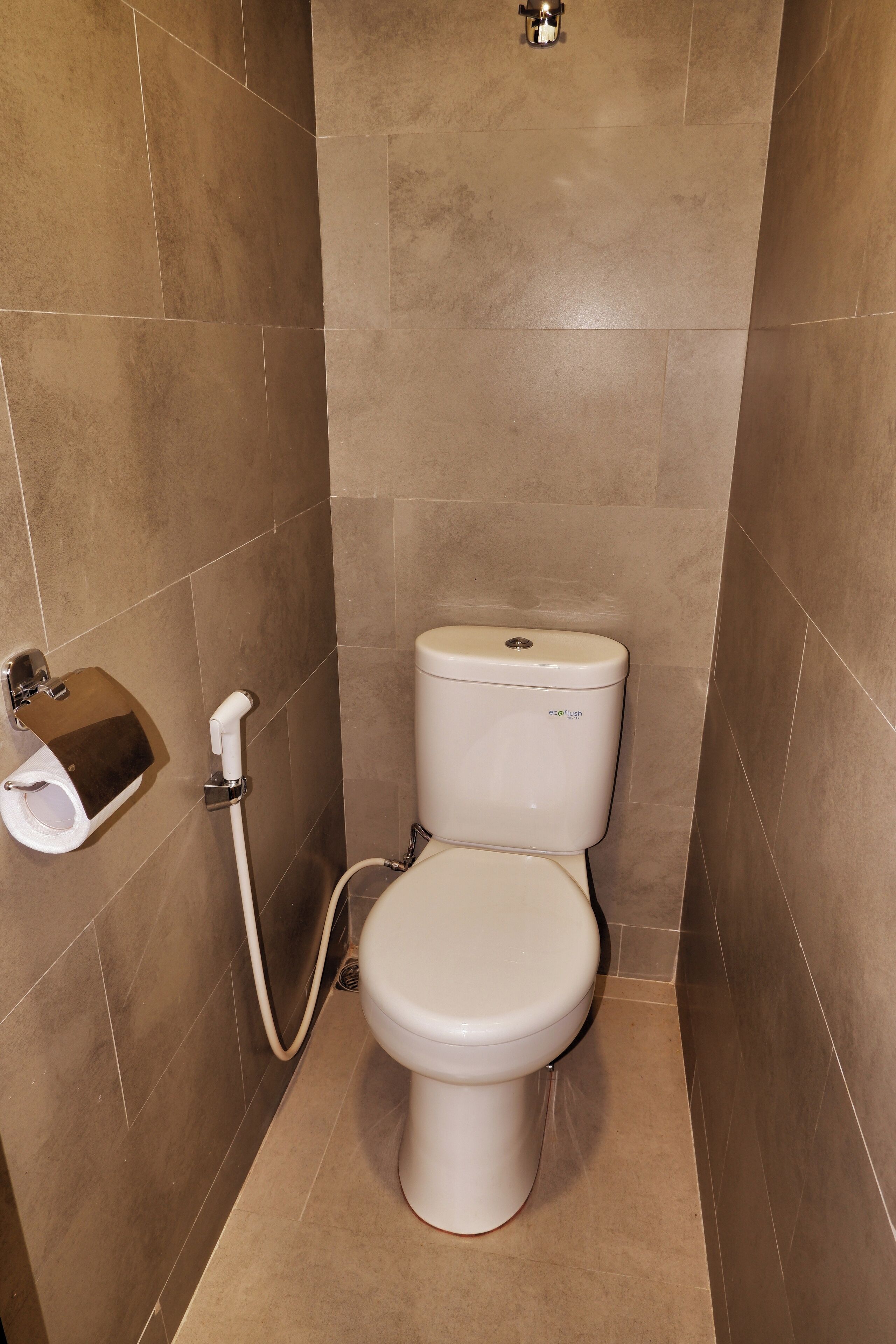 Um banheiro pequeno e moderno, com vaso sanitário, rolo de papel higiênico e chuveiro.